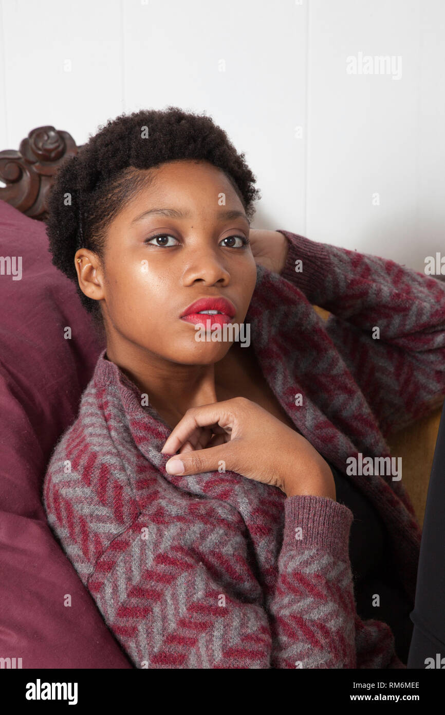 Thoughtful black woman sitting on a couch Stock Photo - Alamy