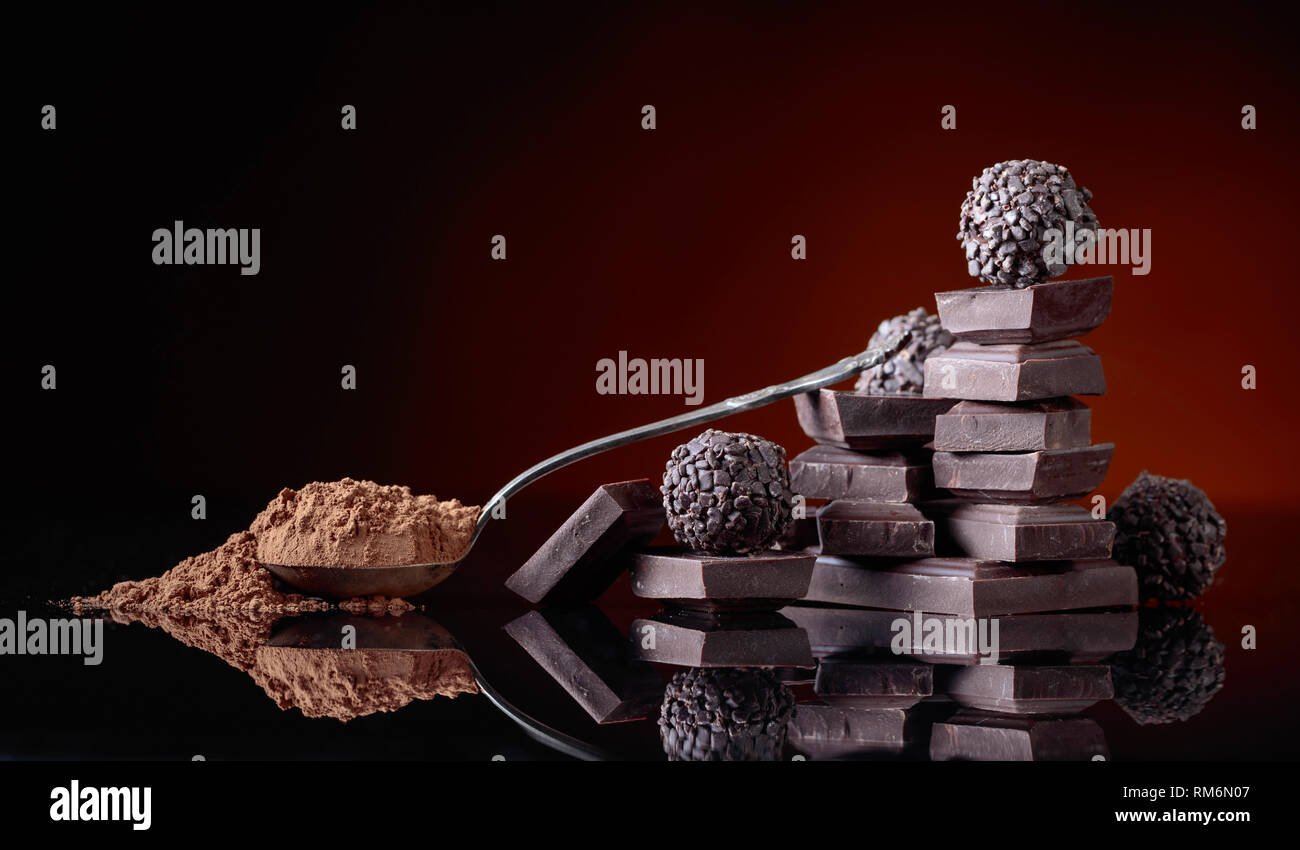 Chocolate candies, broken chocolate pieces and spoon with cocoa powder ...