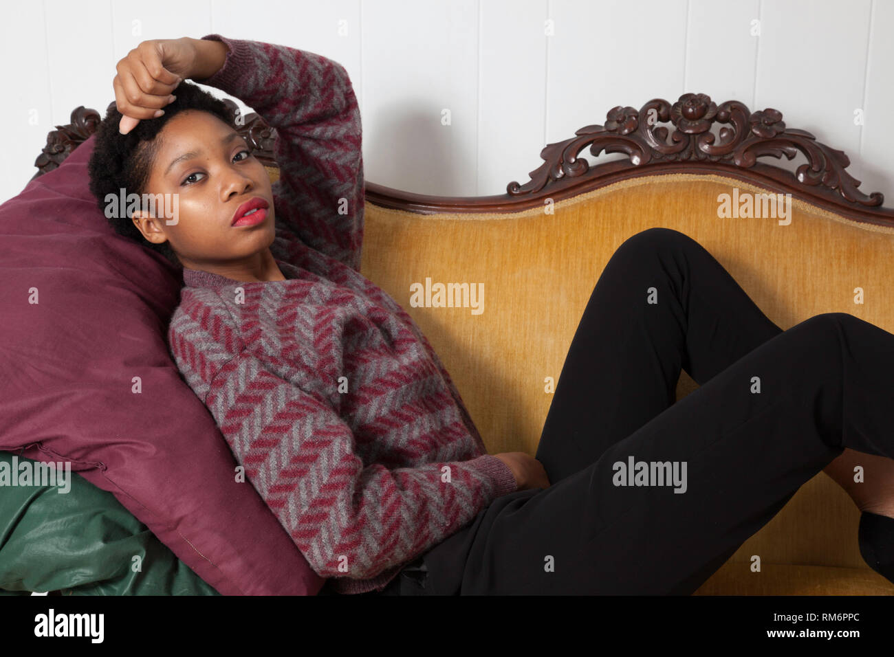 Thoughtful black woman sitting on a couch Stock Photo - Alamy