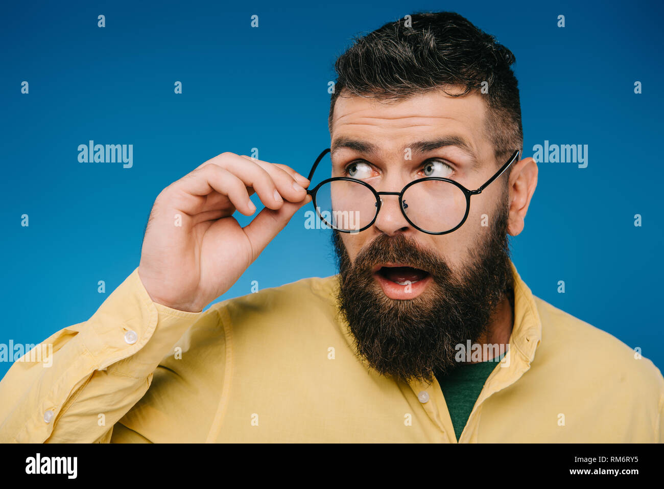 surprised bearded man in eyeglasses isolated on blue Stock Photo - Alamy