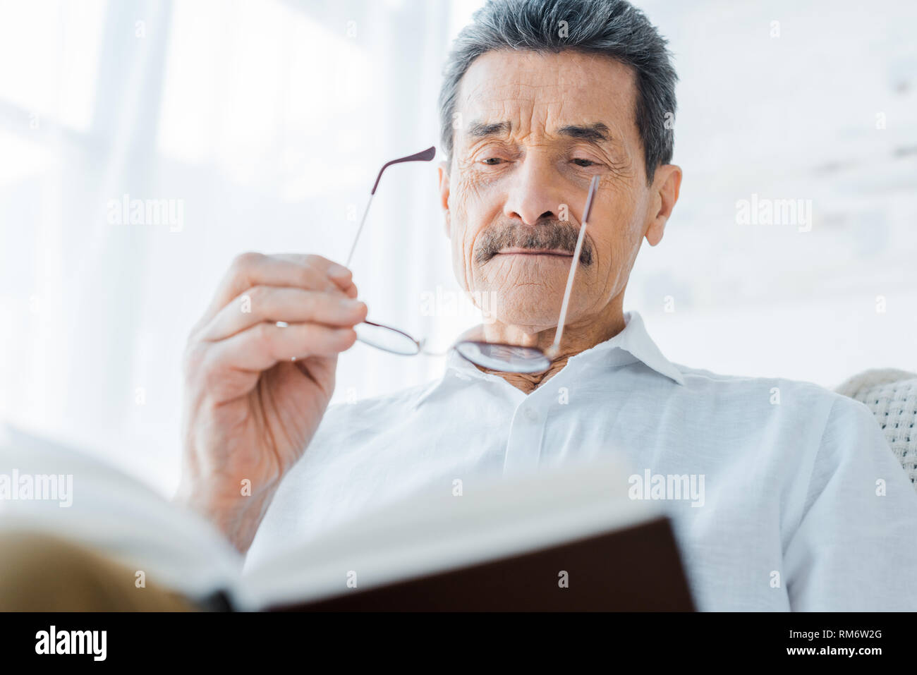 senior man reading book and wearing glasses at home Stock Photo - Alamy