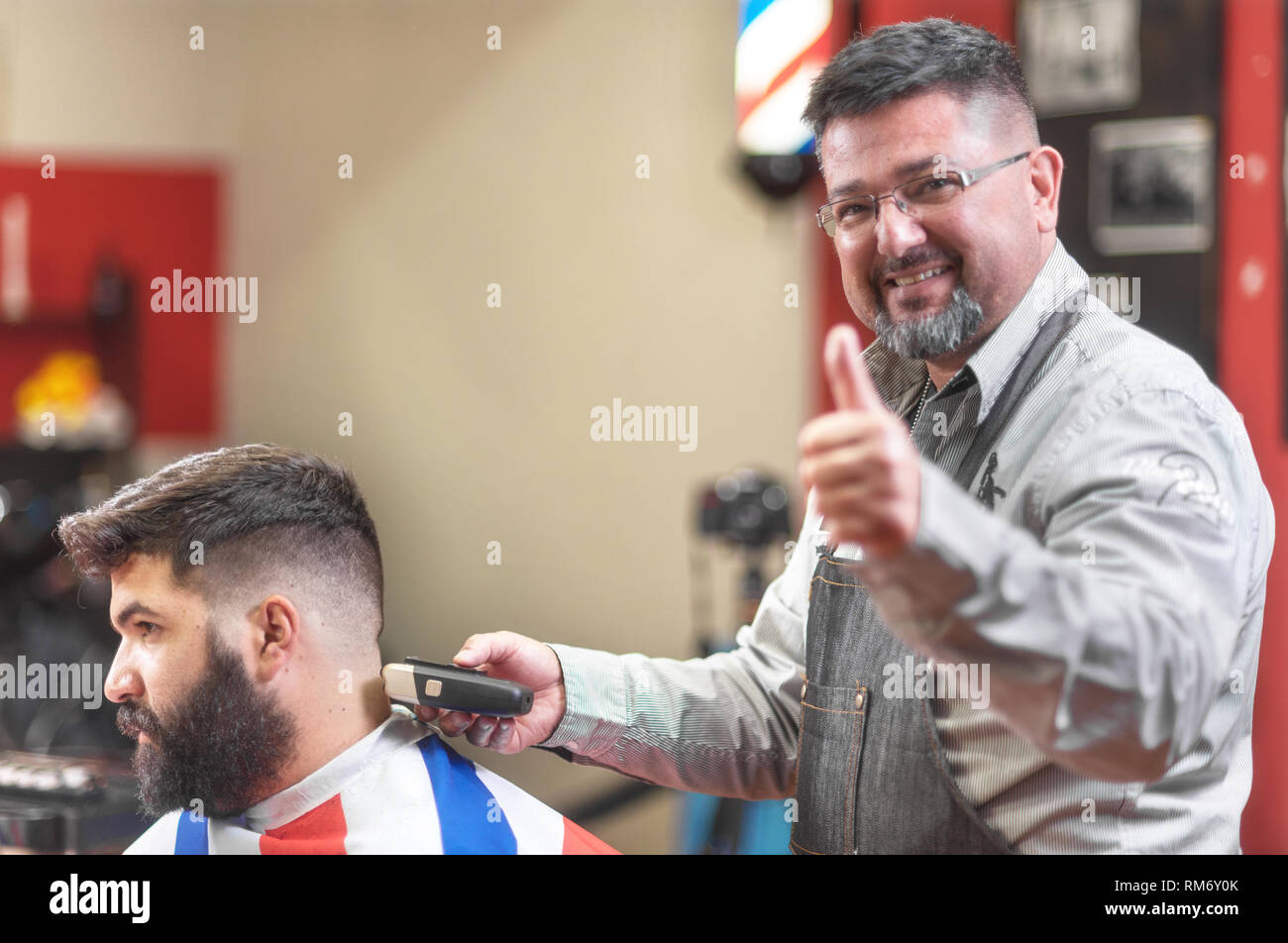 Portrait of a barber working while showing thumb up. Positive approval ...