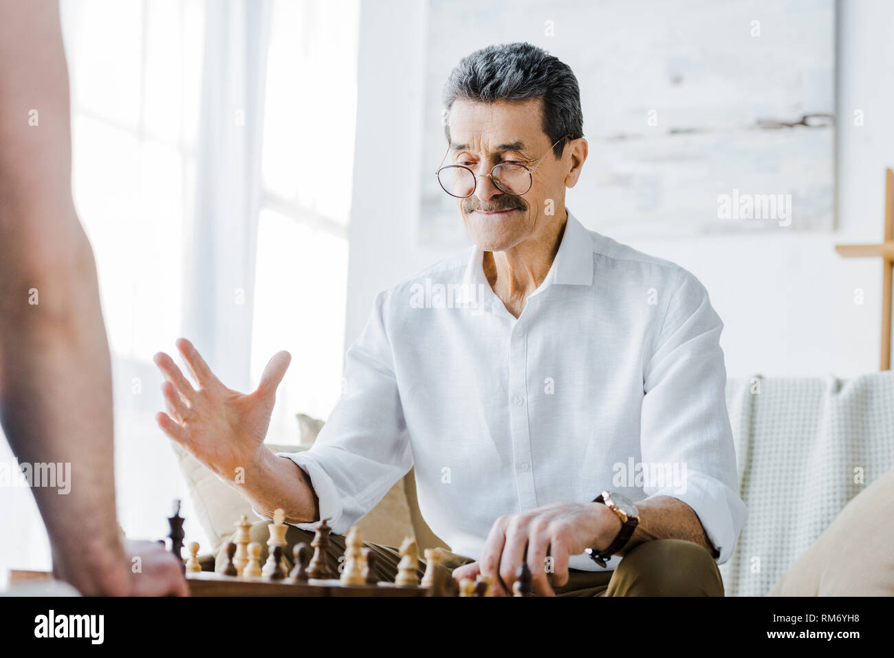 selective focus of senior man with mustache playing chess with friend ...