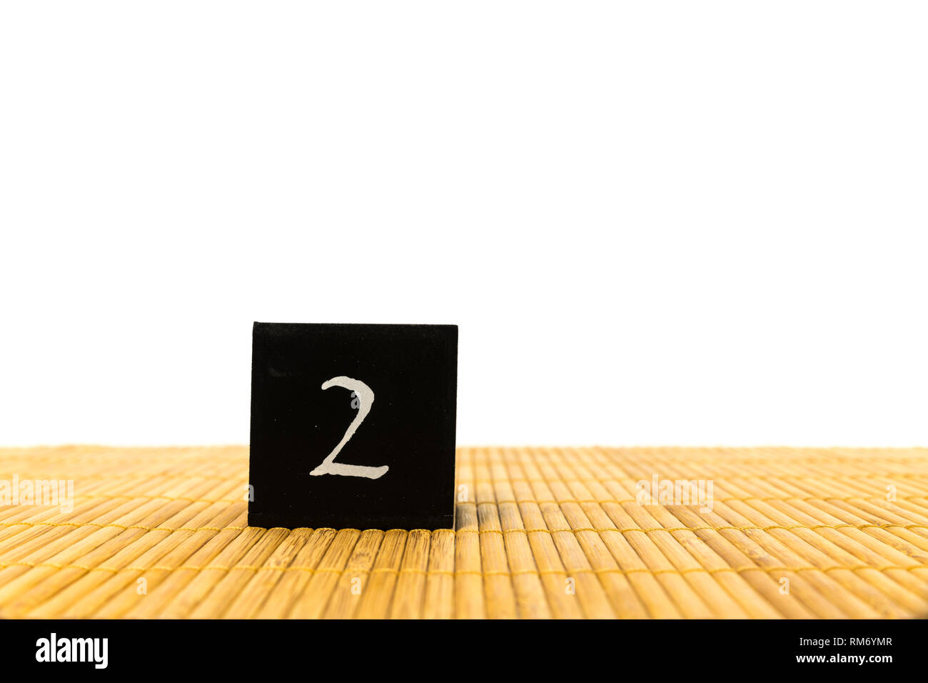 black number 2 block on bamboo underground and with isolated white ...