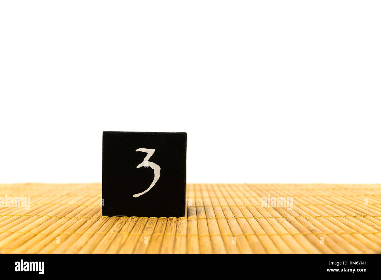 black number 3 block on bamboo underground and with isolated white ...