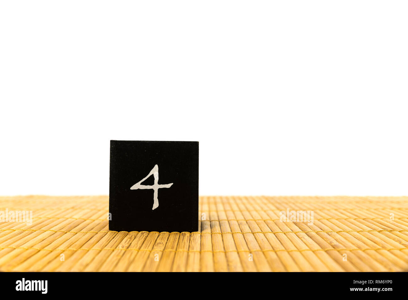 black number 4 block on bamboo underground and with isolated white ...