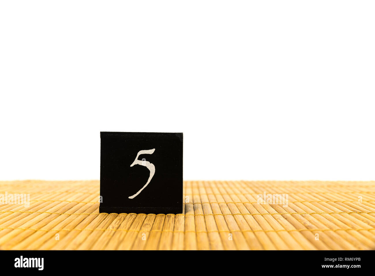 black number 5 block on bamboo underground and with isolated white ...