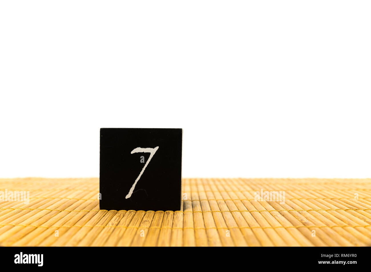 black number 7 block on bamboo underground and with isolated white ...