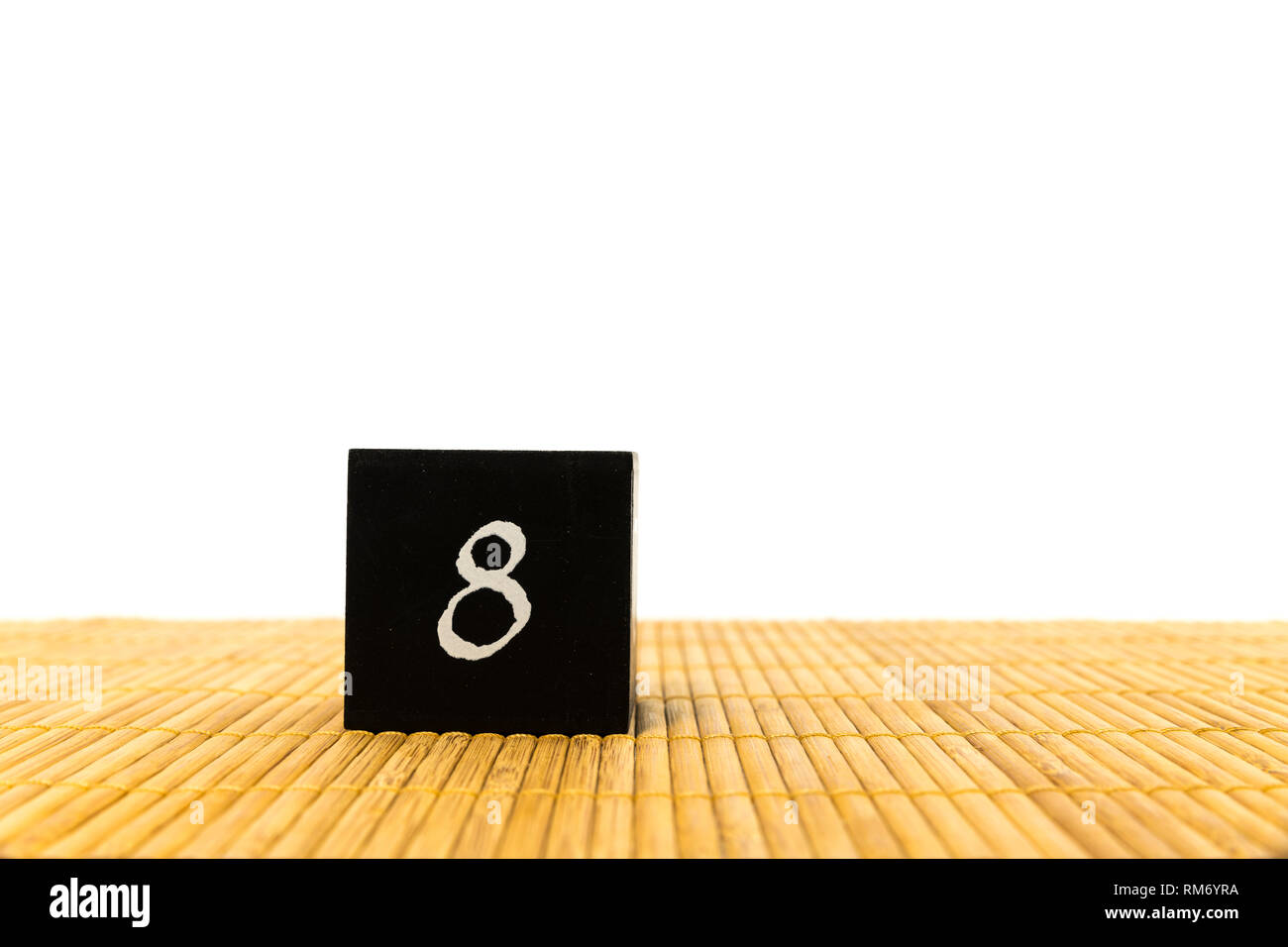 black number 8 block on bamboo underground and with isolated white ...