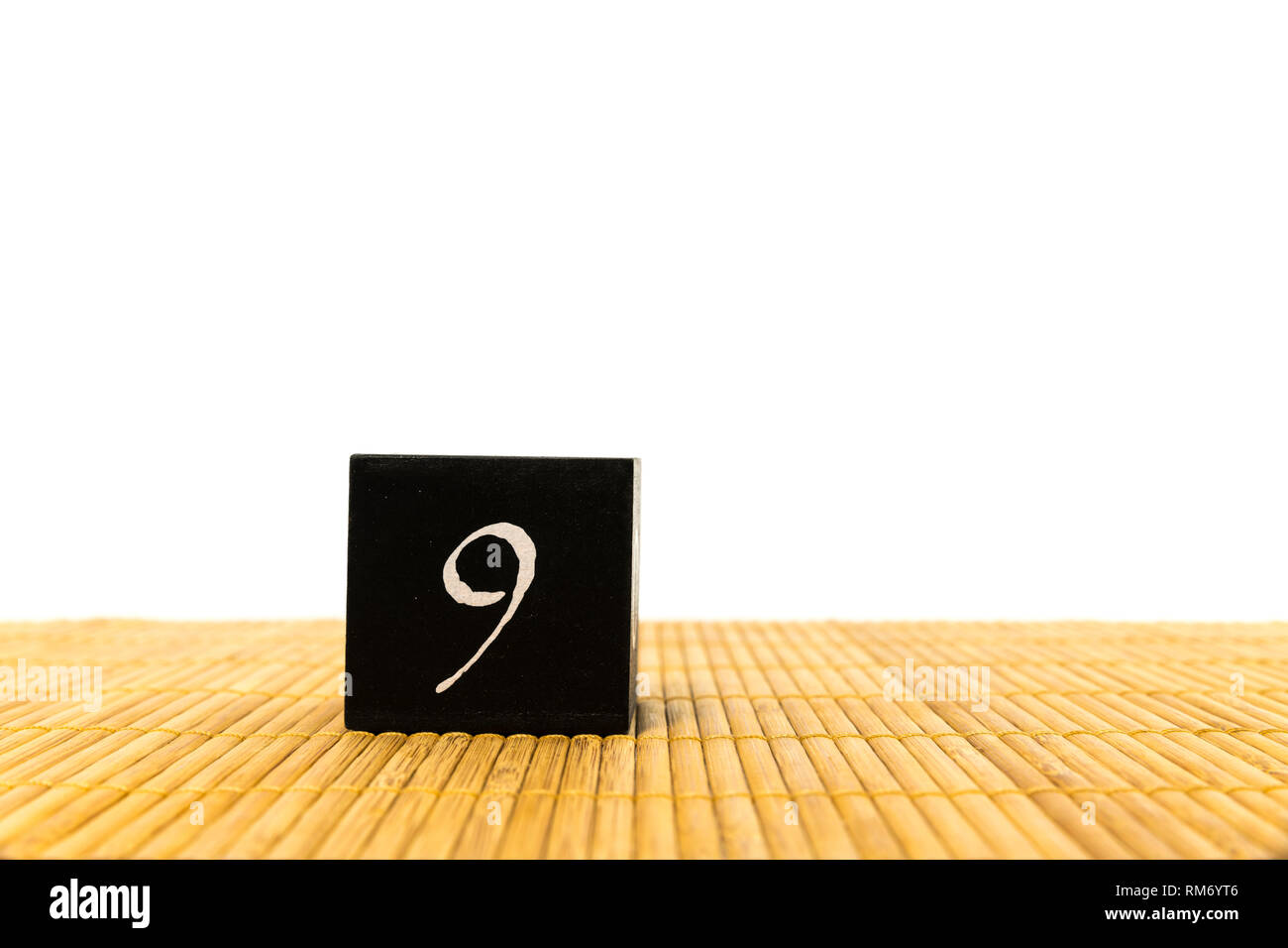 black number 9 block on bamboo underground and with isolated white ...
