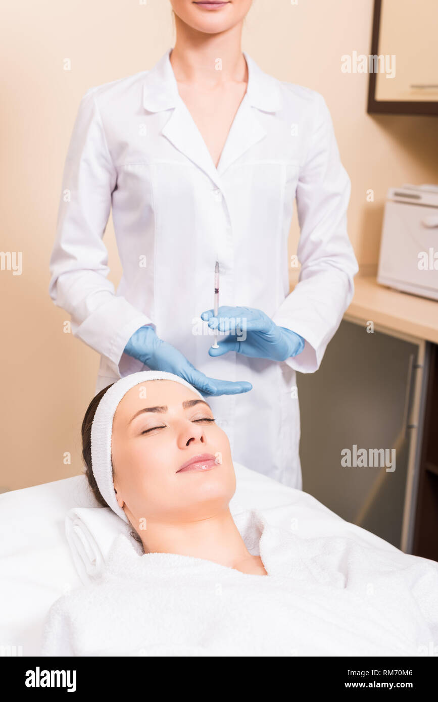 Woman Lying On Massage Table While Beautician Preparing Injection In