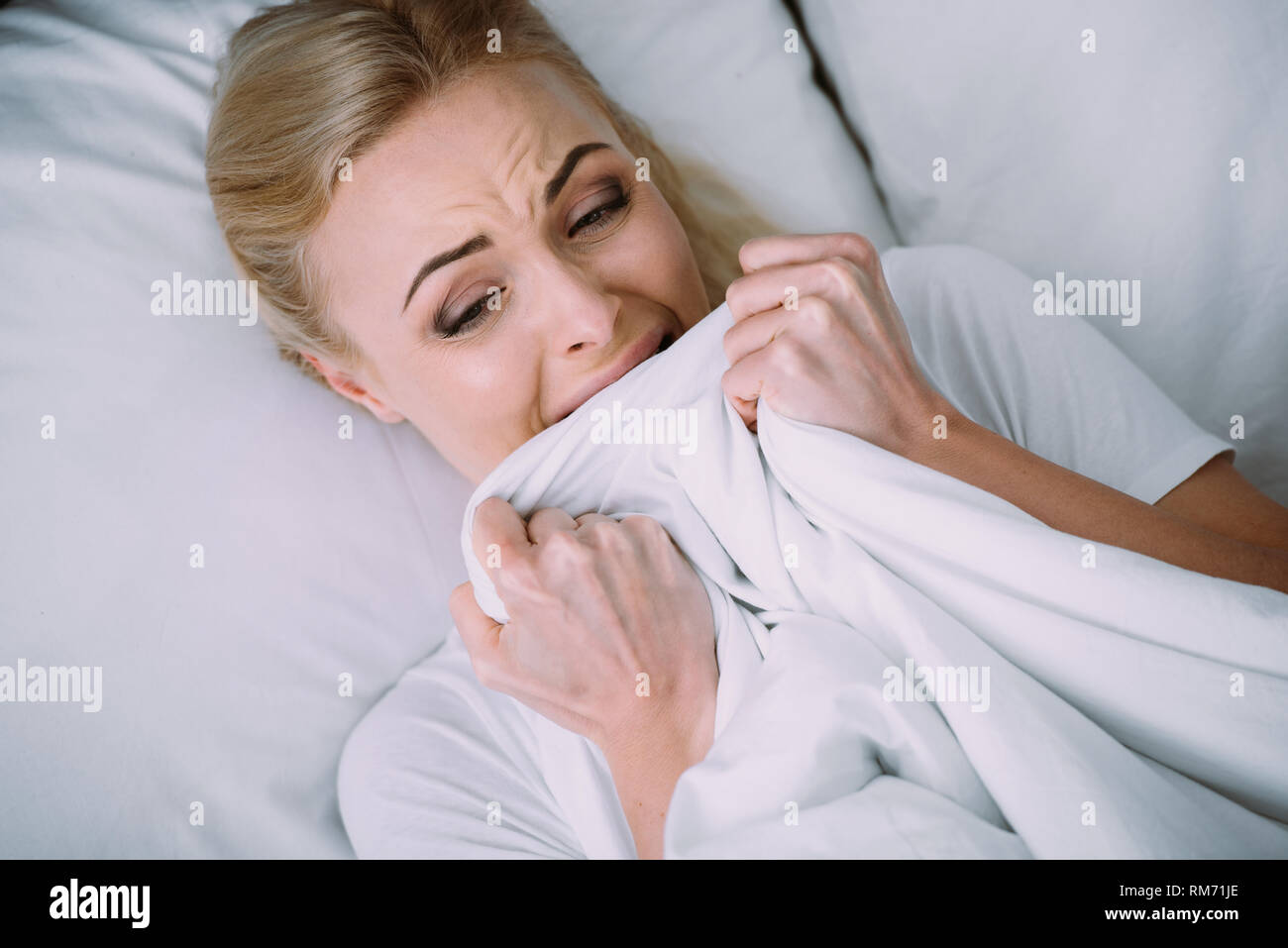 frightened woman lying in bed, crying and holding blanket Stock Photo ...