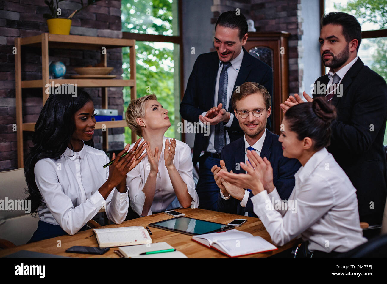 Happy businesspeople clapping hands at the meeting Stock Photo - Alamy