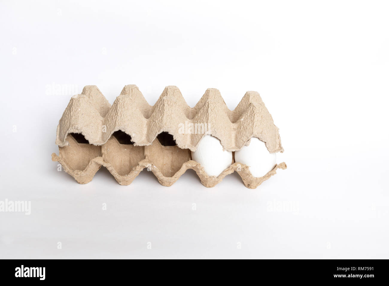 Closed half-empty cardboard box with white eggs in middle of white ...