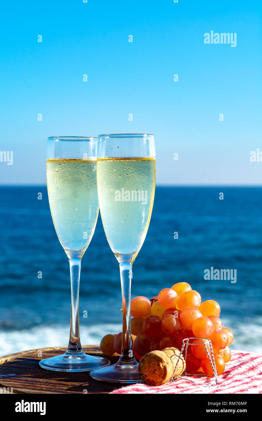 Champagne, prosecco or cava served with pink grape in two glasses on ...
