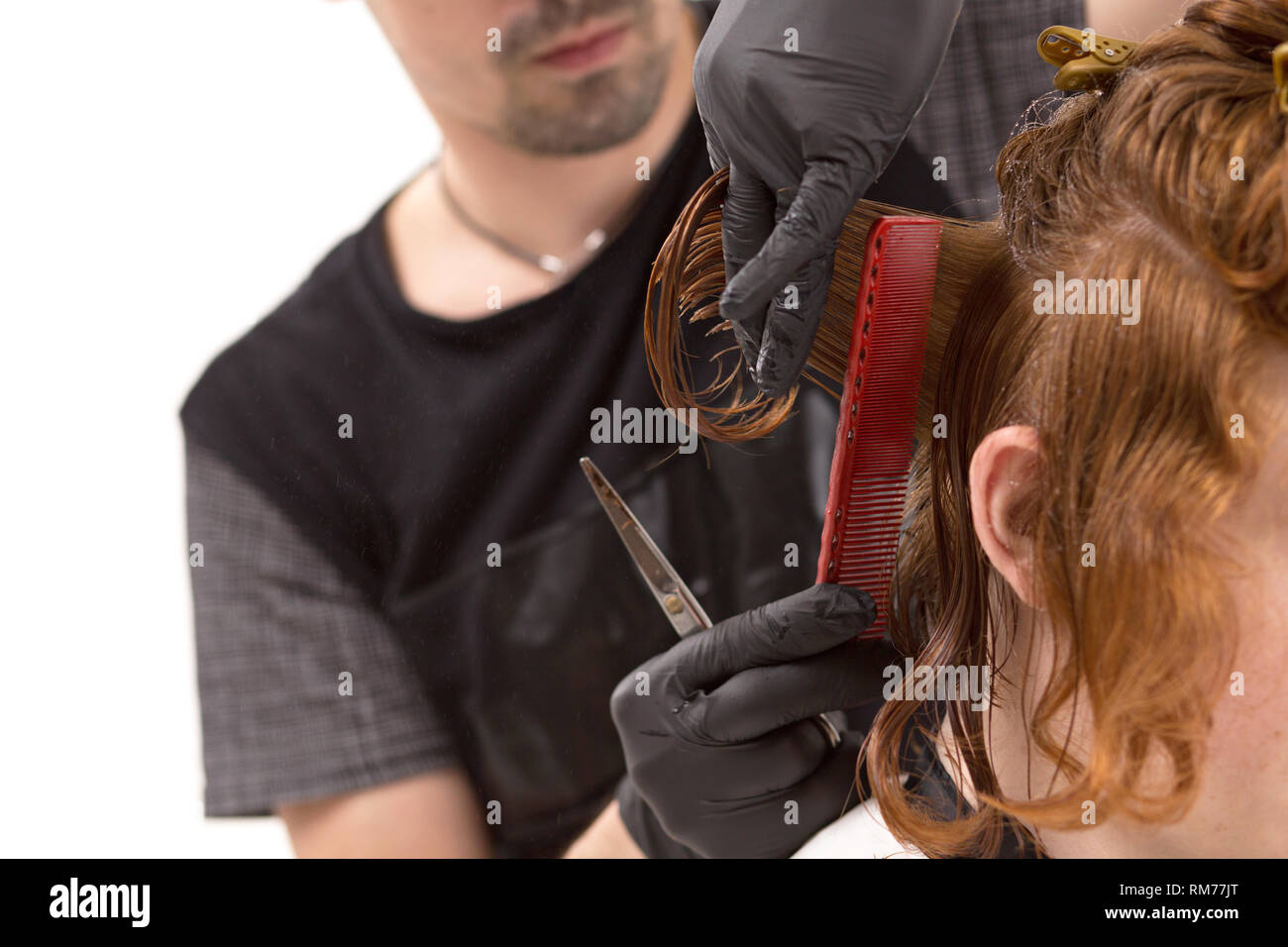 Barber holds between fingers lock of hair before cutting it off ...