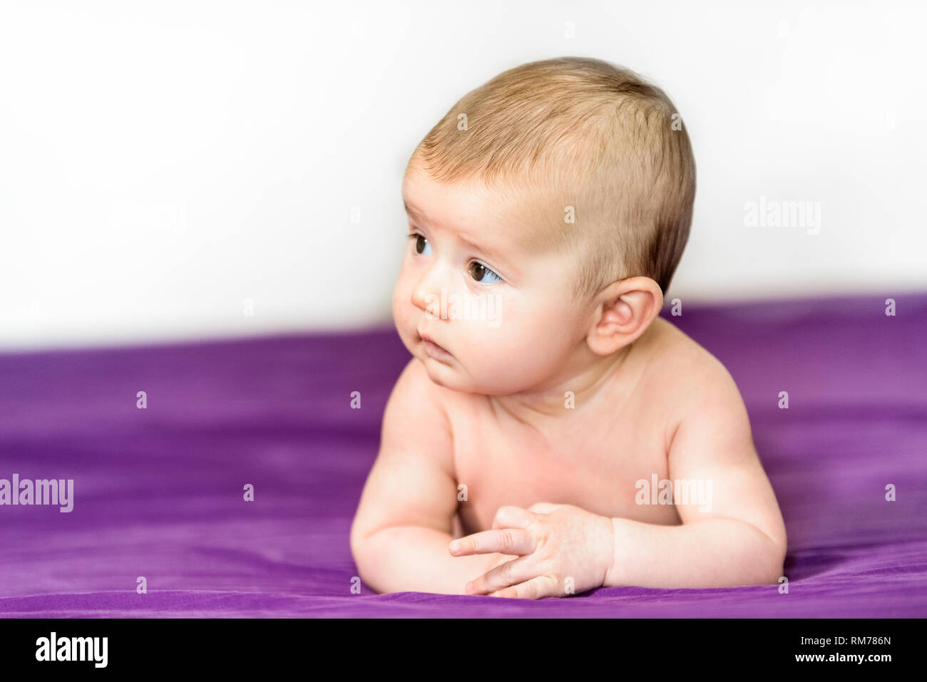 Newborn blonde baby 3 months old lying on her stomach and head raised ...