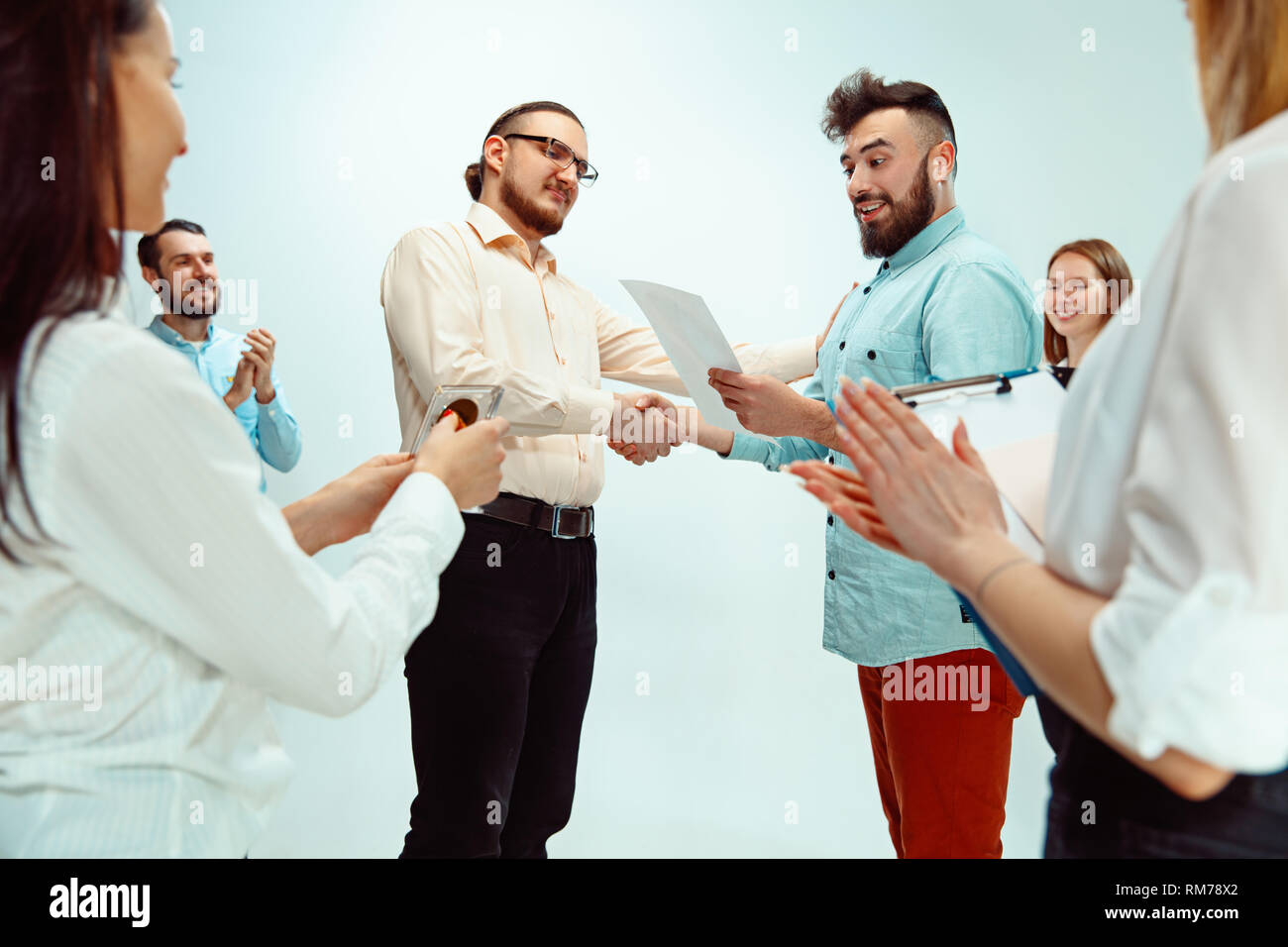 Boss approving and congratulating young successful employee of the ...