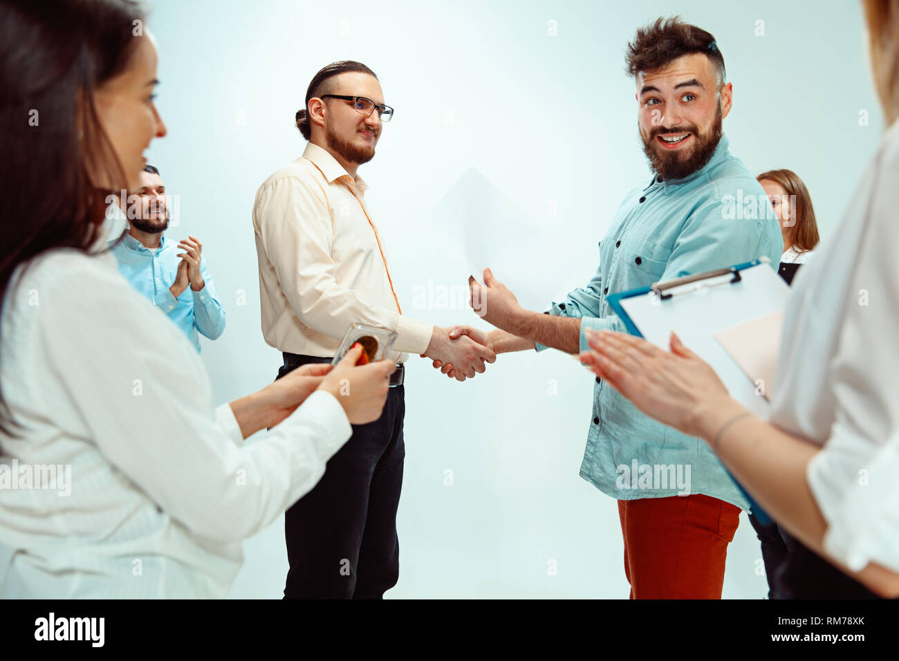 Boss approving and congratulating young successful employee of the ...