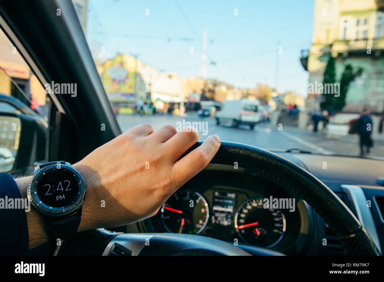 man driving car in city traffic looking on watch. first person view ...