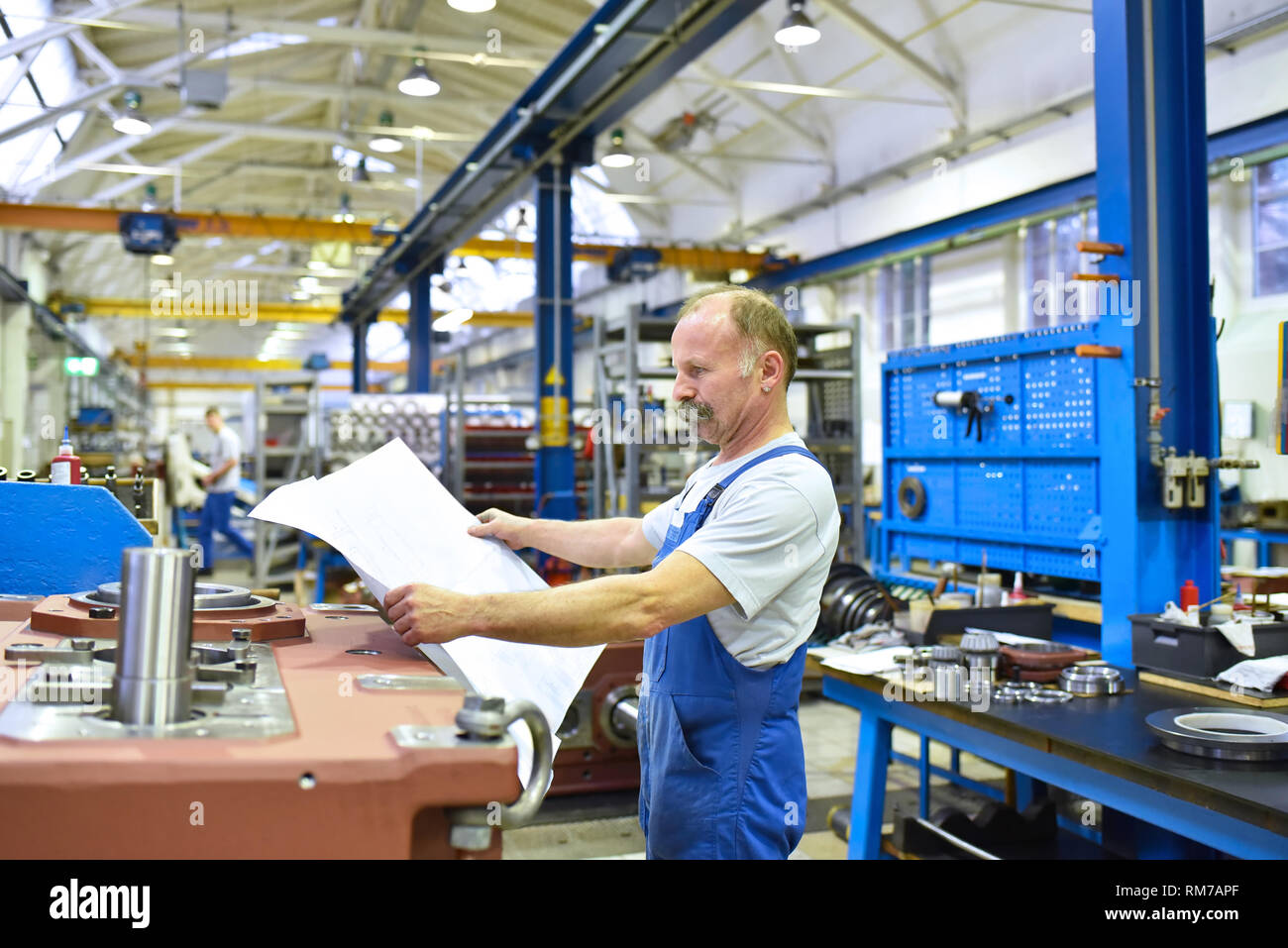 older worker in mechanical engineering - industrial factory for the ...