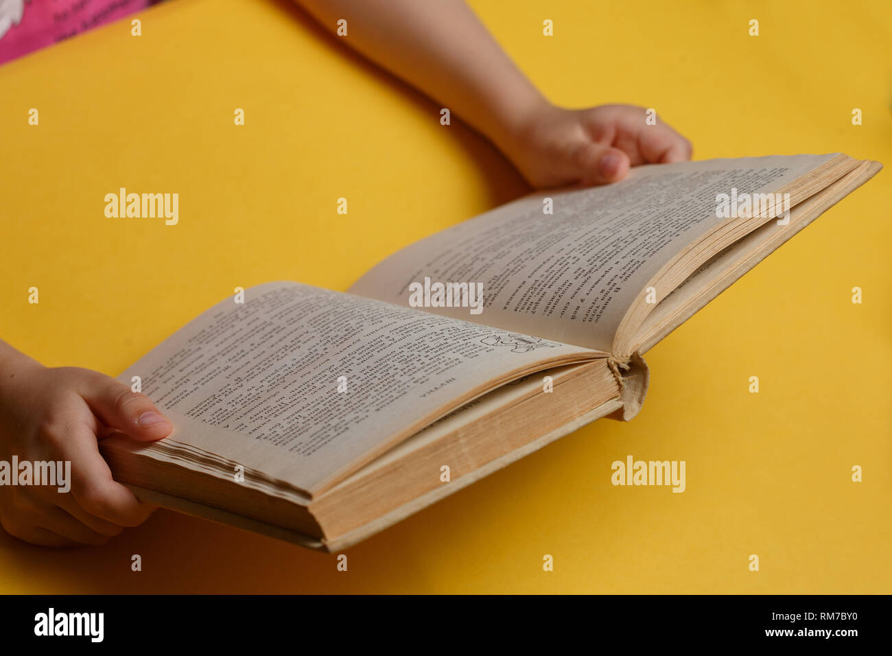 Anonymous child girl holding open book in hands with love to reading ...