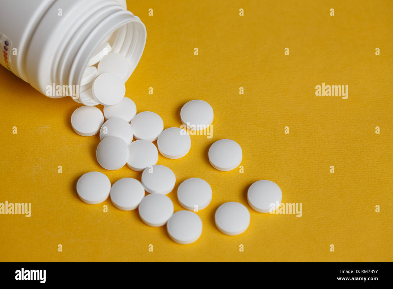 Vitamins (drugs) scattered and spilled out near an opened white plastic ...