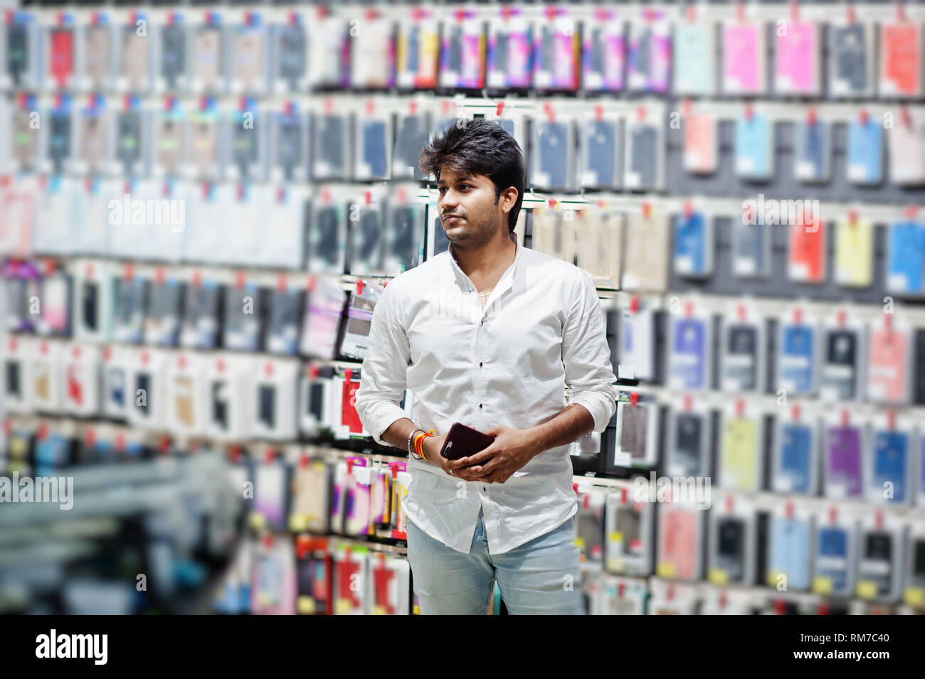 Indian man customer buyer at mobile phone store choose a case for his ...