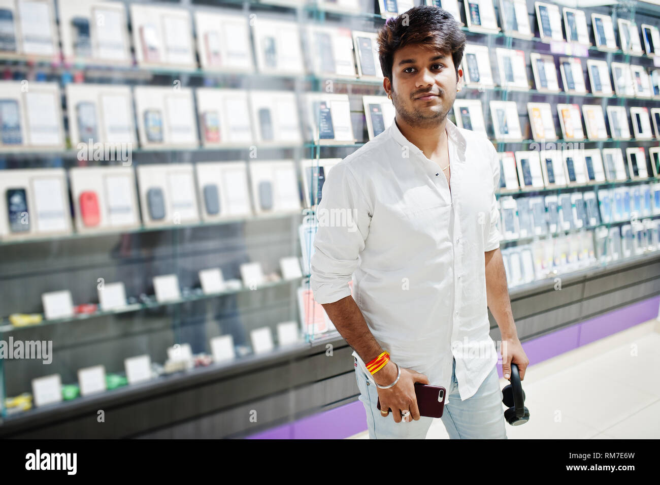 Indian man customer buyer at mobile phone store with wireless earphones ...