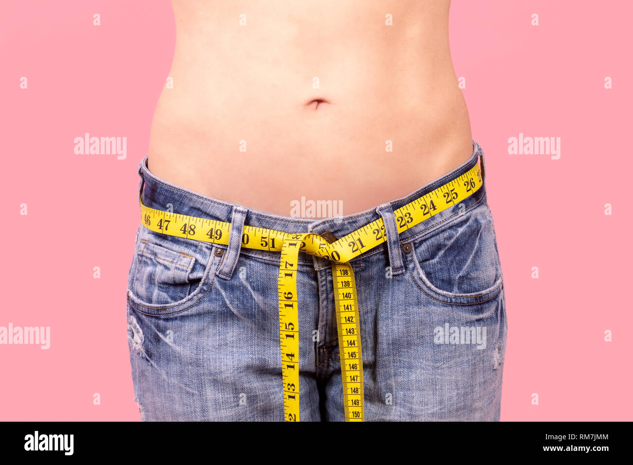 woman with a tape measure around her jeans showing waist measurement ...