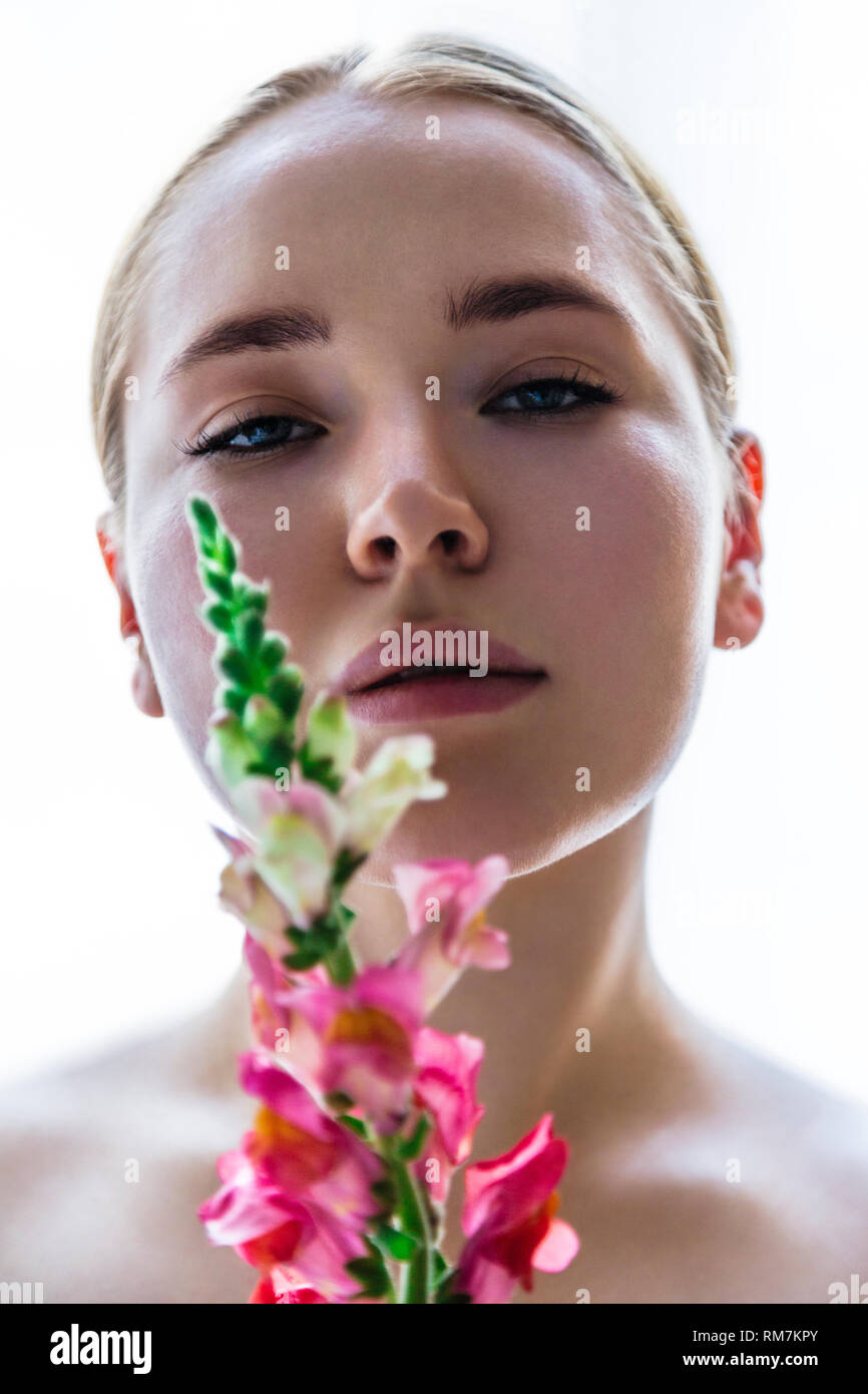 Beautiful young girl smelling bright snapdragon flower Stock Photo - Alamy