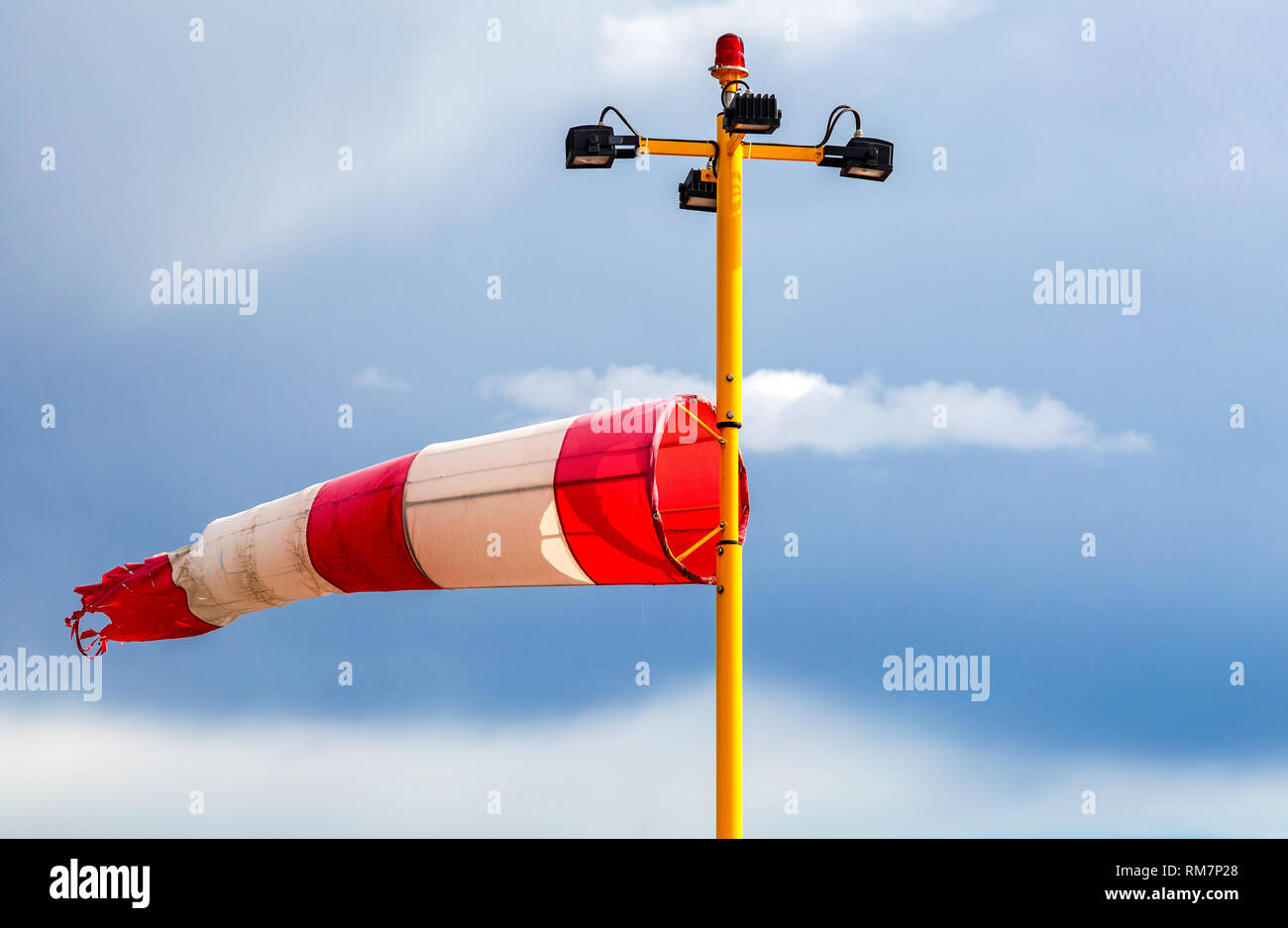 Horizontally flying windsock wind vane with red and white lines against ...