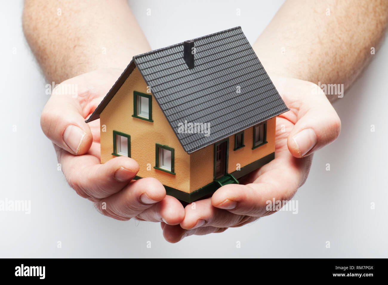 The male hands are holding a house, isolated on the white background ...