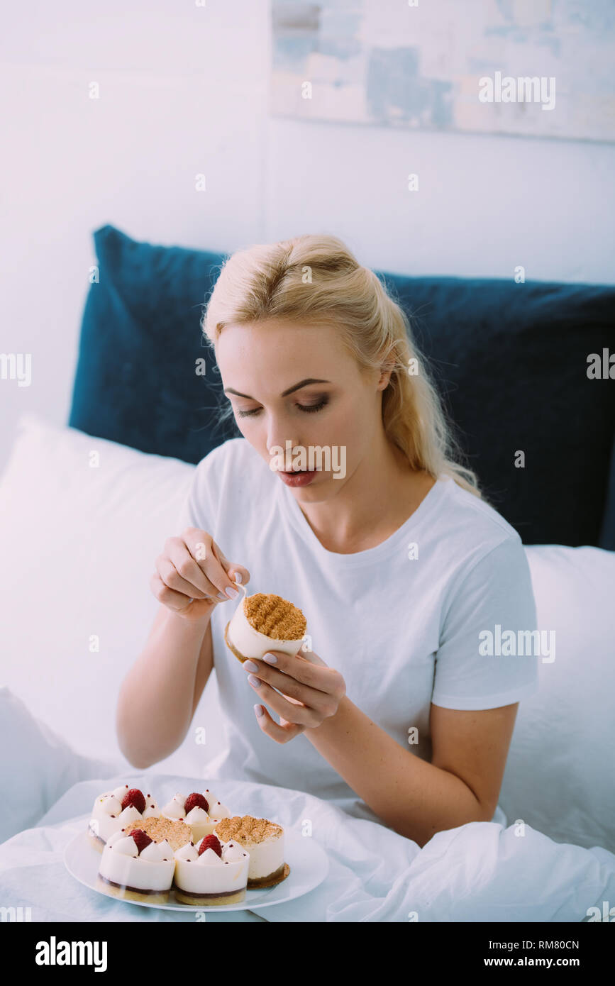 beautiful sad woman in white pajamas eating cake in bed alone Stock ...