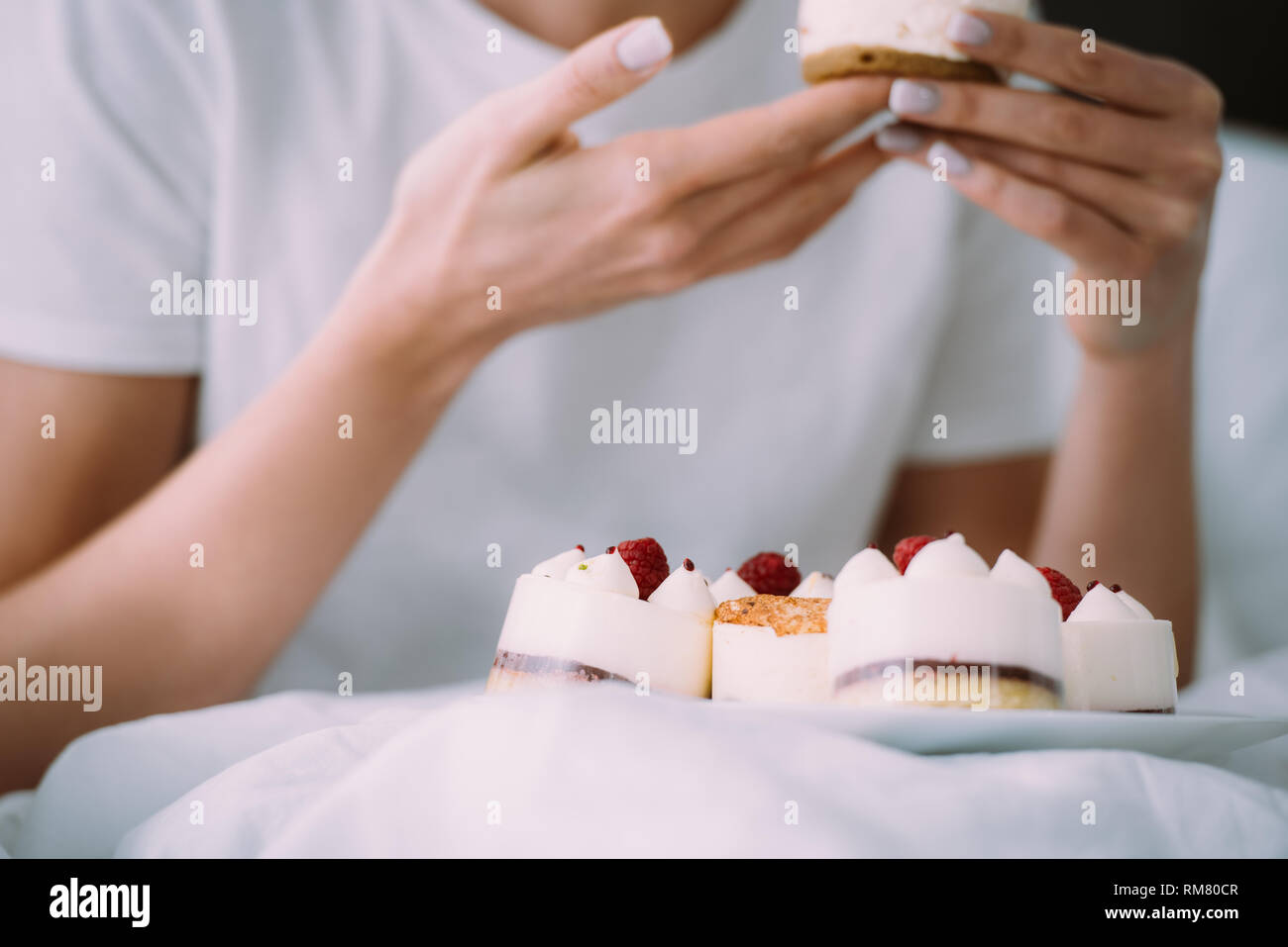 cropped view of woman eating cake in bed Stock Photo - Alamy