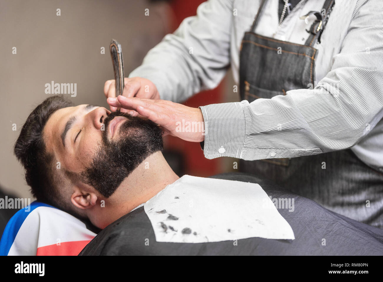 Handsome man having a shave with vintage razor at the barbershop Stock ...