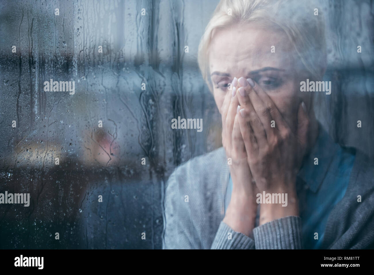 sad adult woman crying and covering face with hands at home through ...