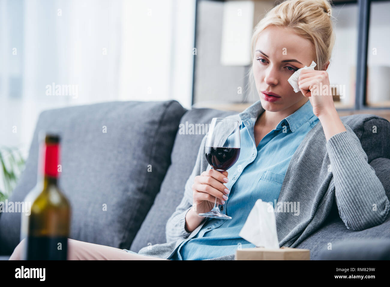 upset woman with glass of wine crying and wiping tears with tissue at ...