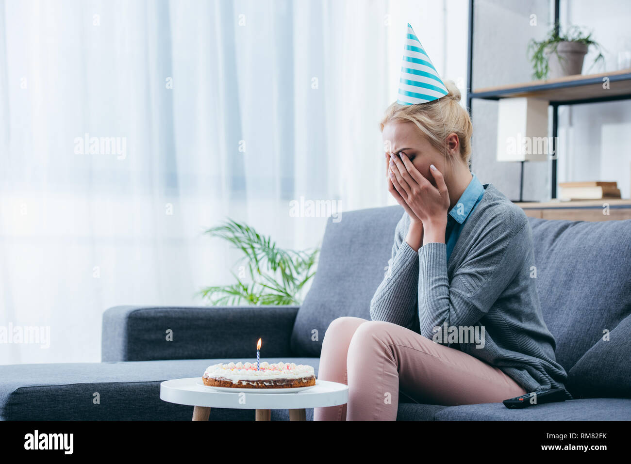 upset woman in party hat crying while celebrating birthday at home ...