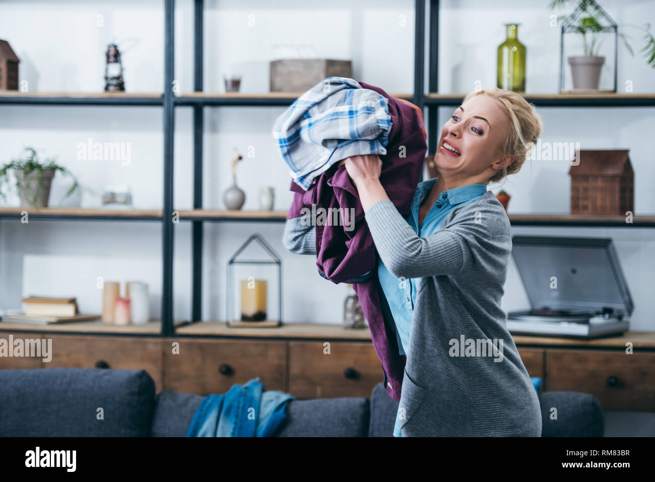 angry woman throwing clothes in living room after breaking up with ...