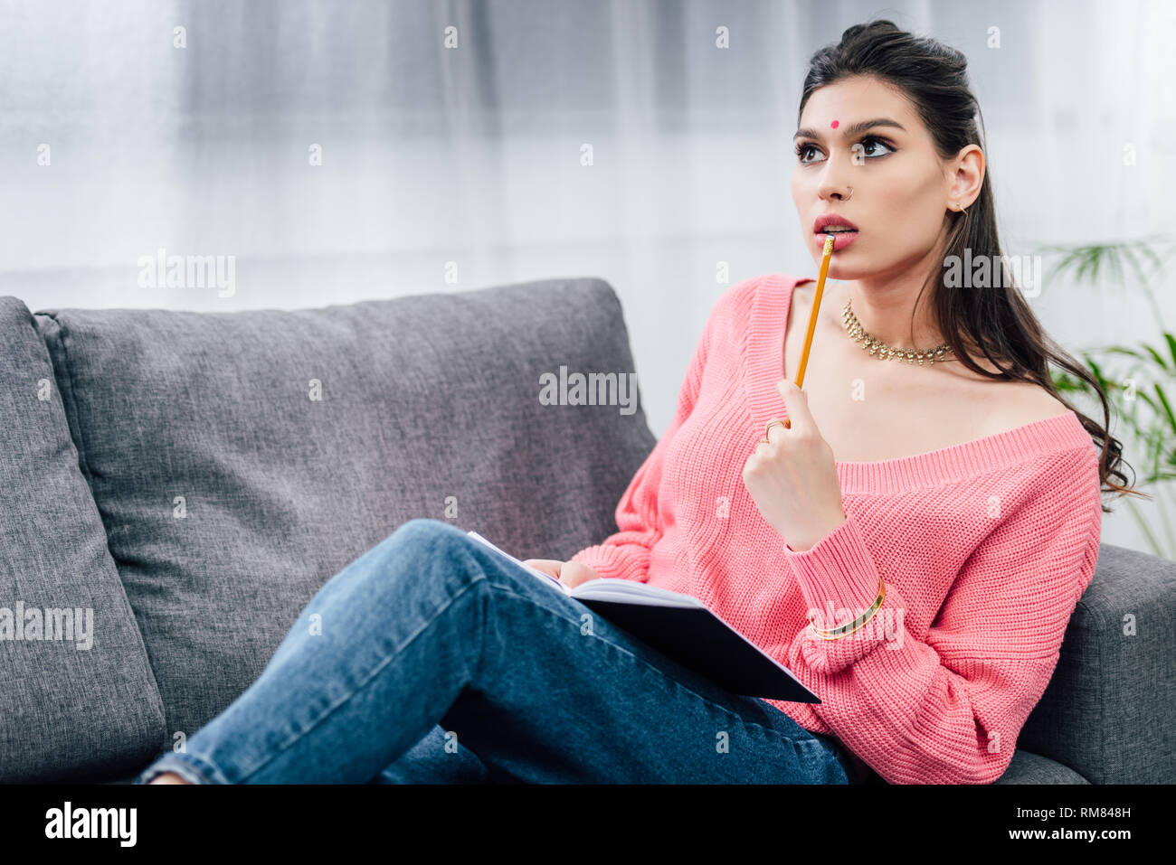 female indian student thinking and writing in notebook Stock Photo - Alamy