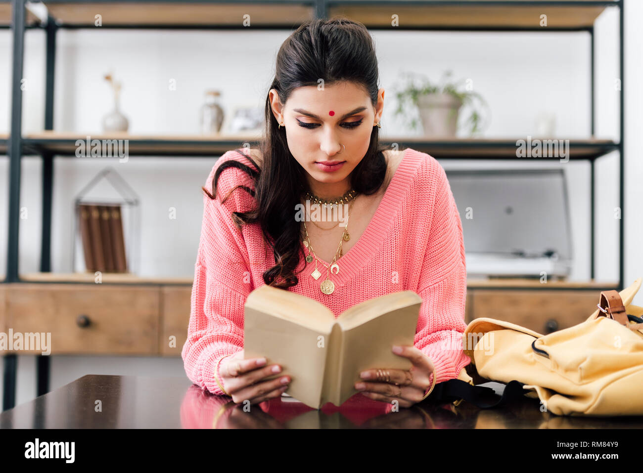 beautiful indian woman with bindi studying at home and reading book ...
