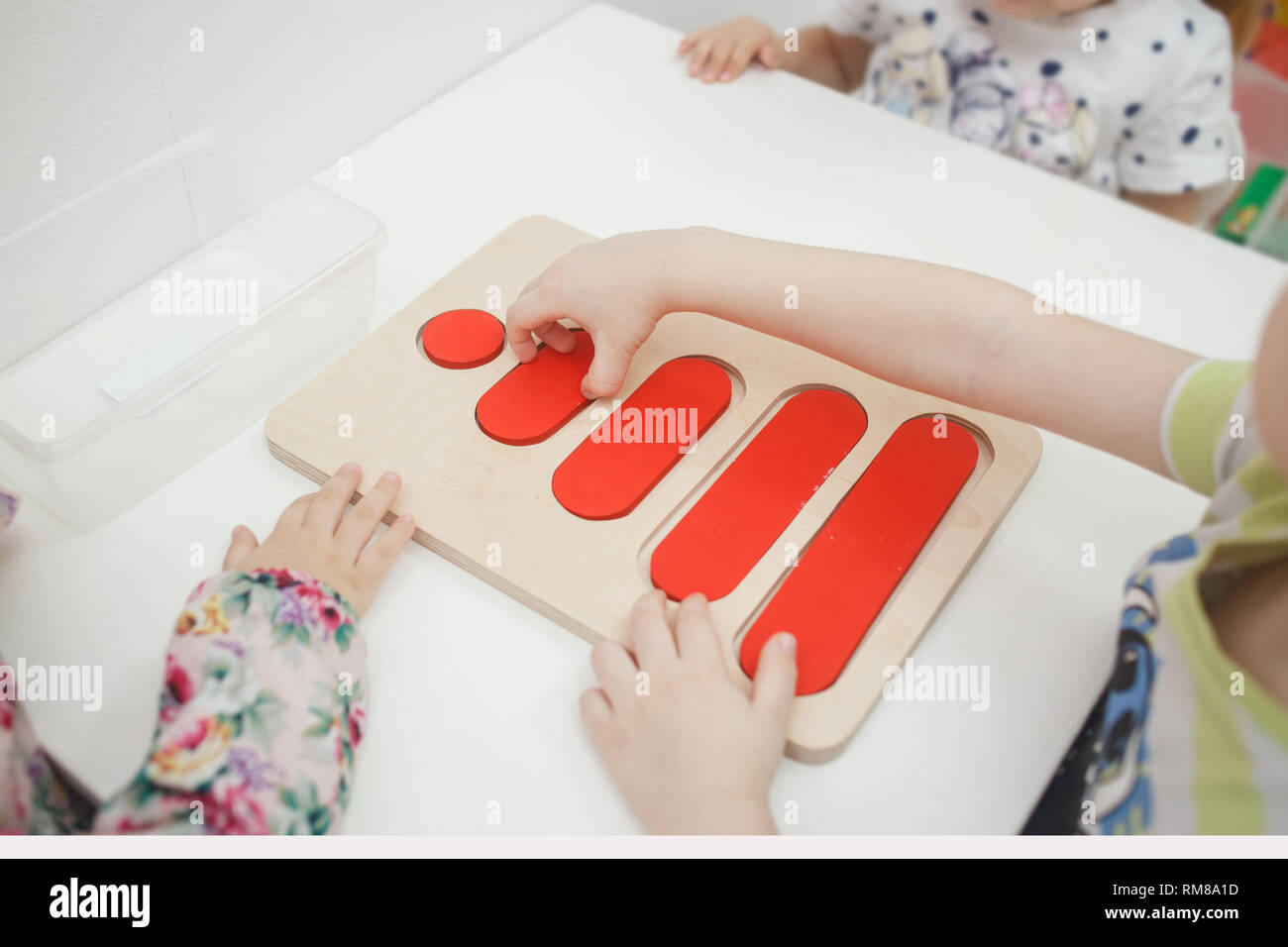 Toddlers playing multicolored educational games, mosaic and puzzles ...