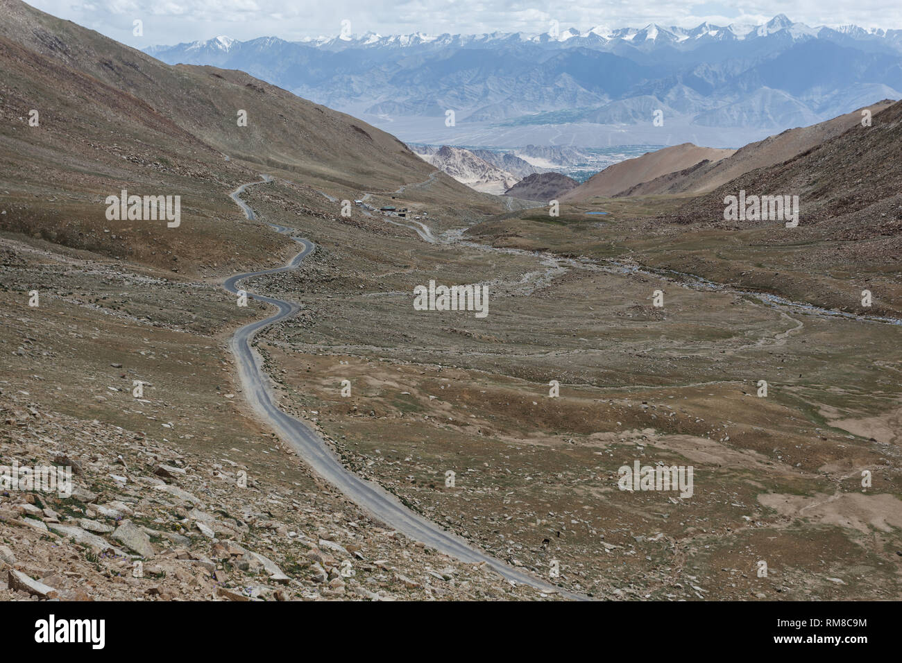 Mountain biking the narrow dirt road ahead winding over the barren mountains of the Khardungla ...