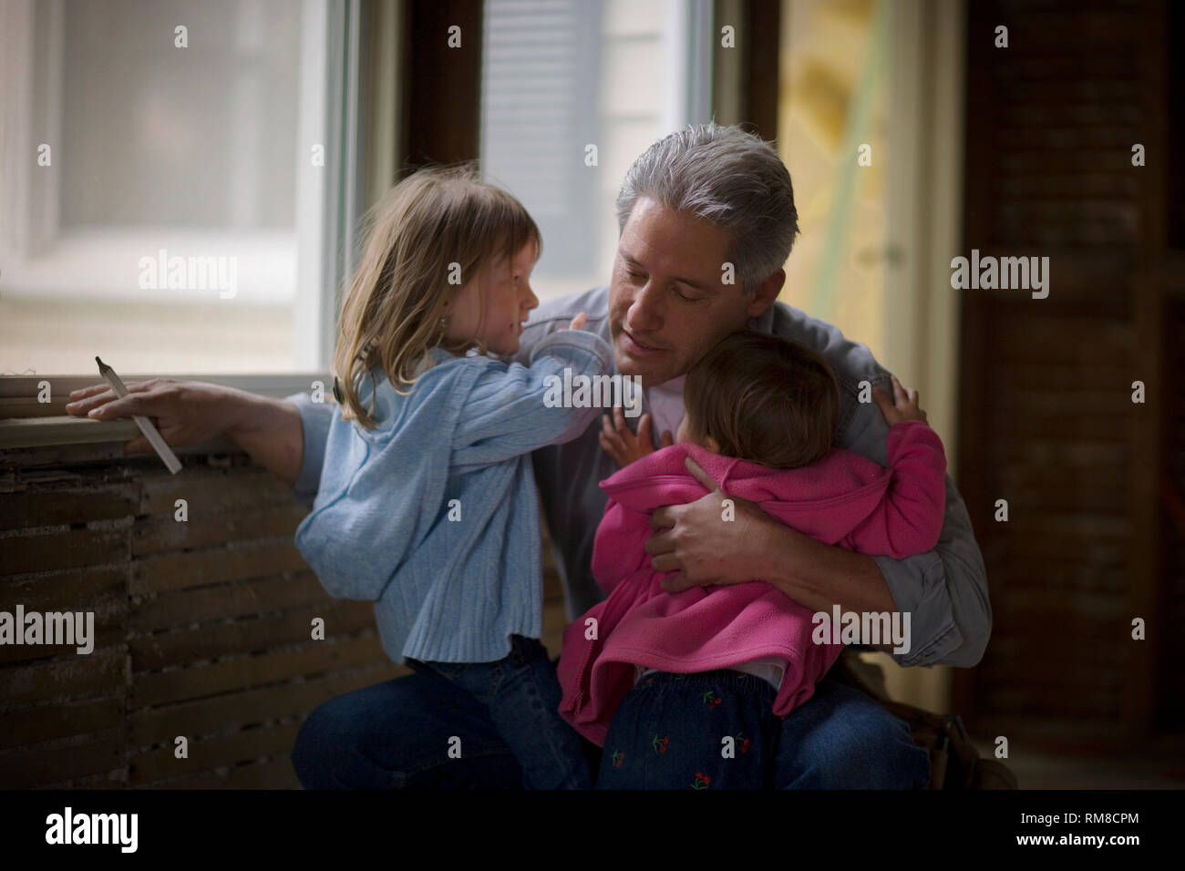 Mid-adult man hugging his two young daughters Stock Photo - Alamy