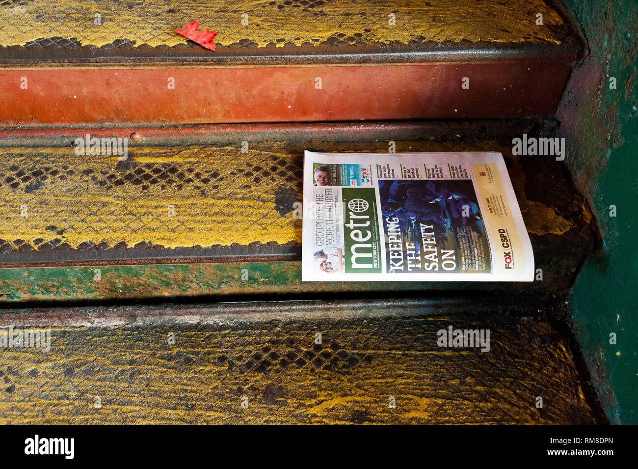 Metro newspaper lying on subway staircase. Colourful worn treads of a ...