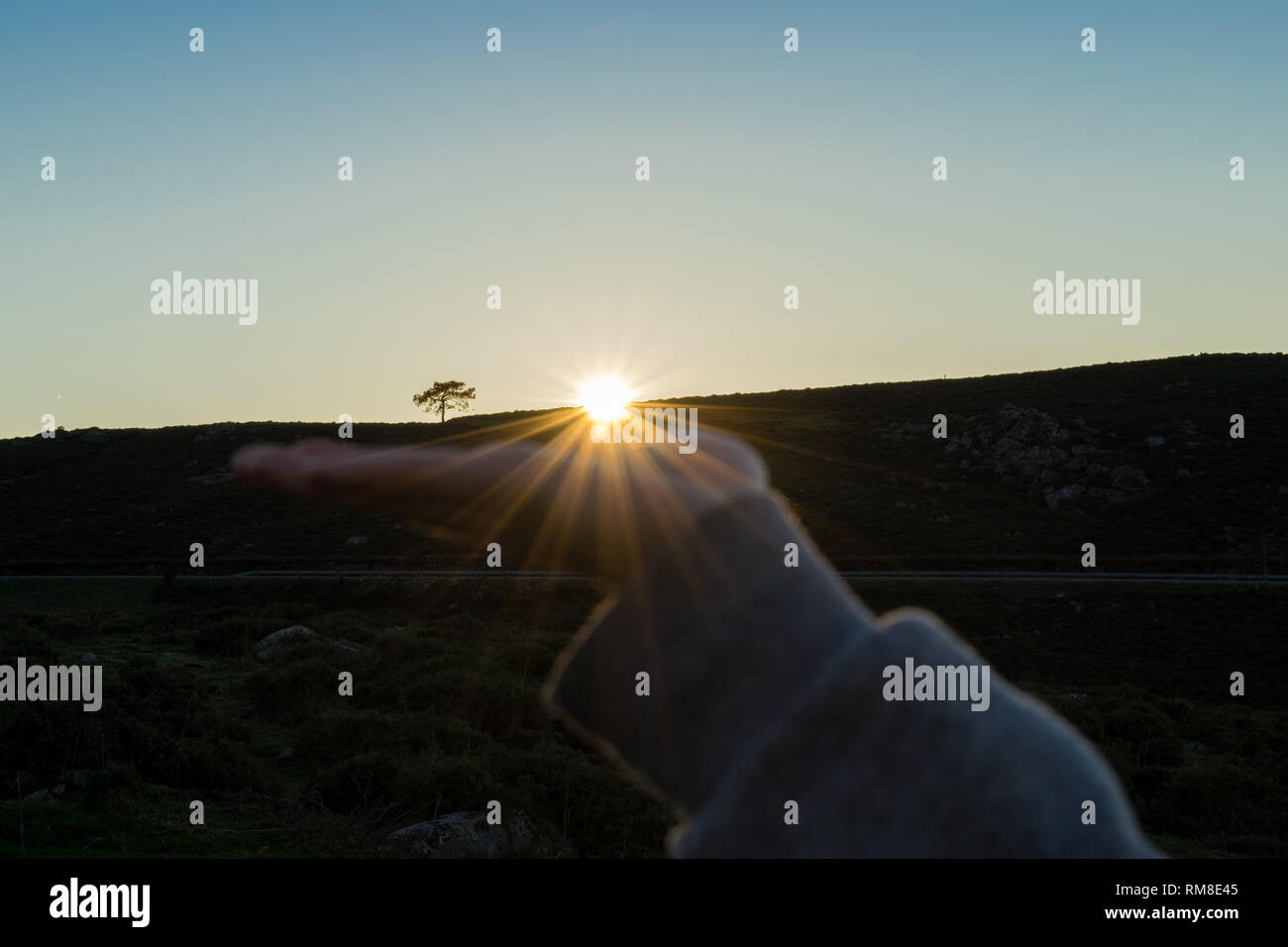 Optical illusion of hand holding sun at sunset in the mountain Stock ...