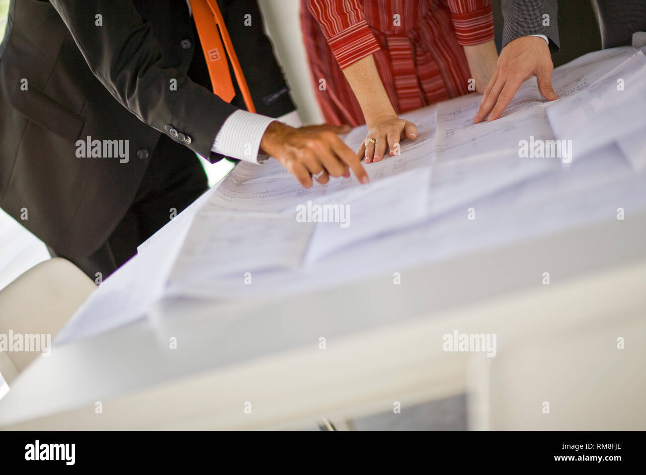 Business people pointing at plans on a table in an office Stock Photo ...