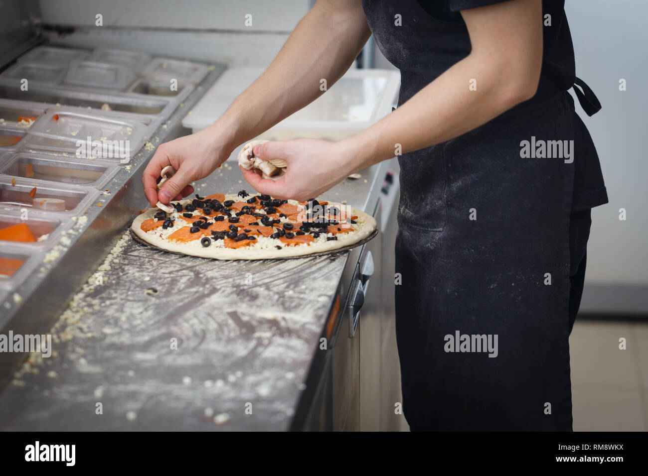 Baker lays the stuffing on the pizza in the fast food restaurant Stock ...