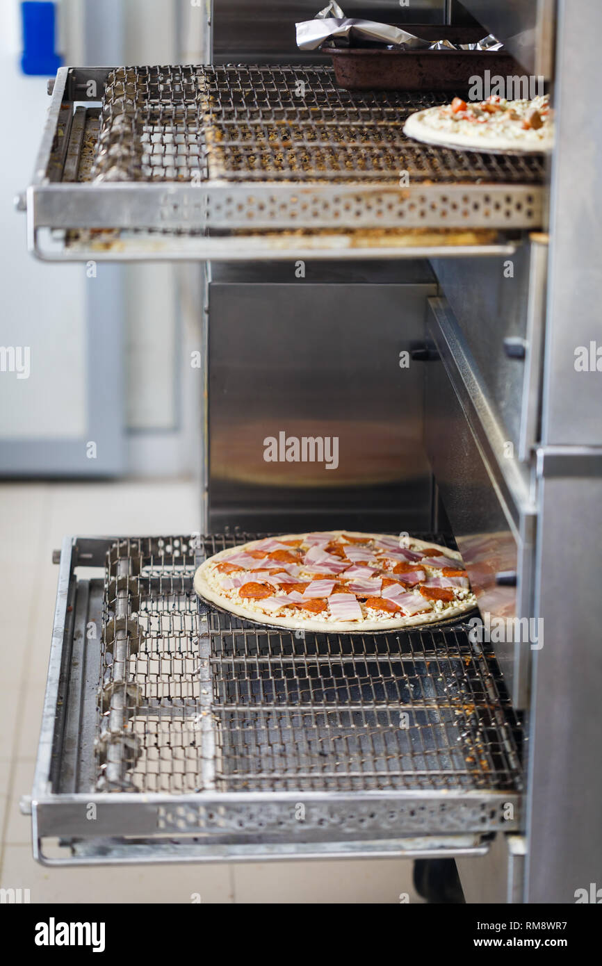 Several pizzas are in the oven in the fast food restaurant Stock Photo ...